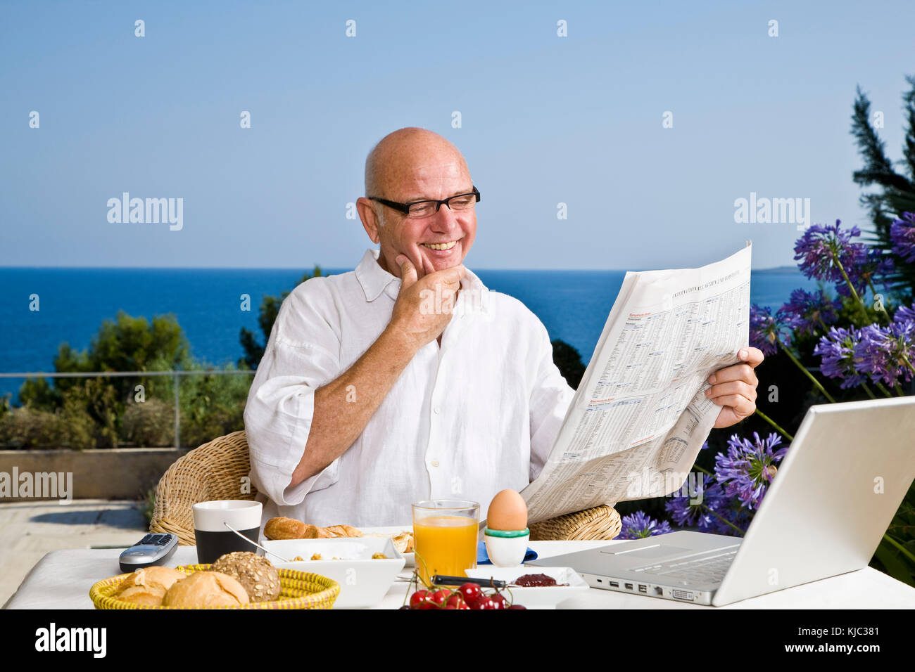 Man on Patio Eating Breakfast and Reading Newspaper Stock Photo - Alamy