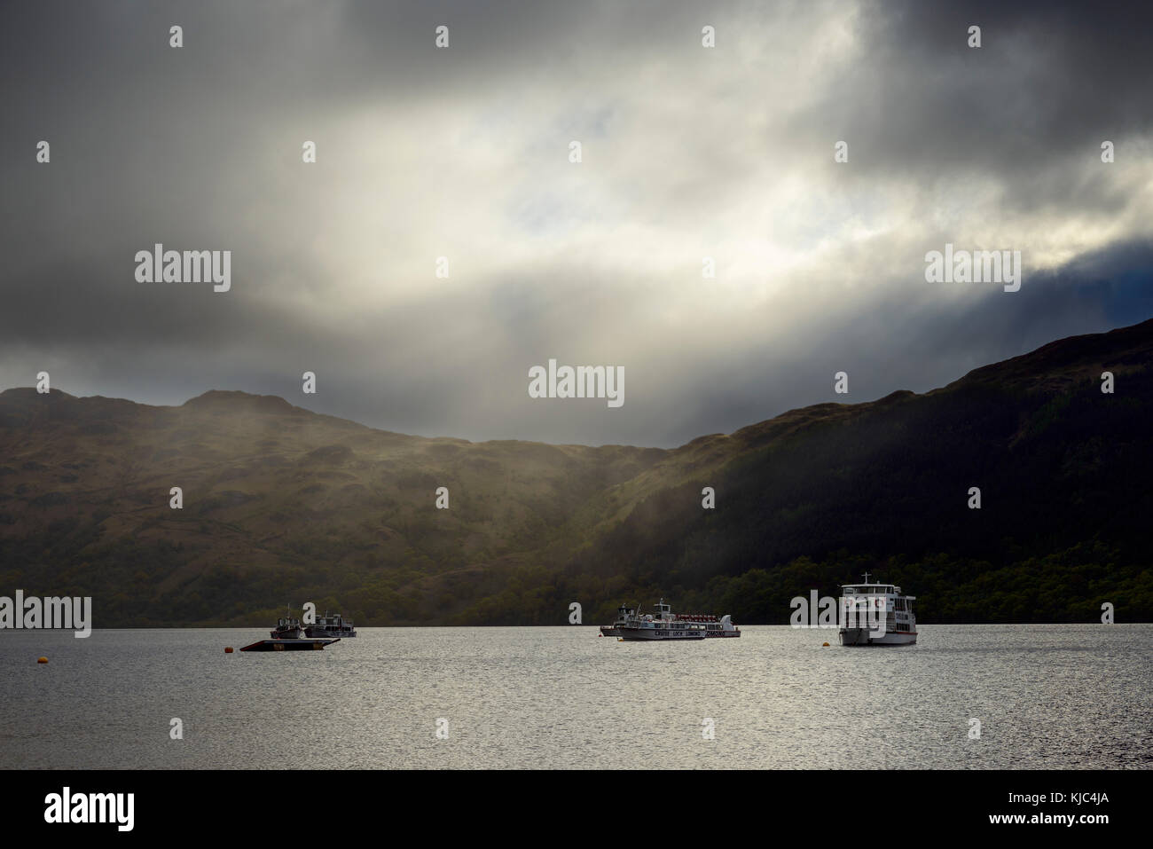 Cruise ships on lake with dramatic clouds and light at Loch Lomond in ...