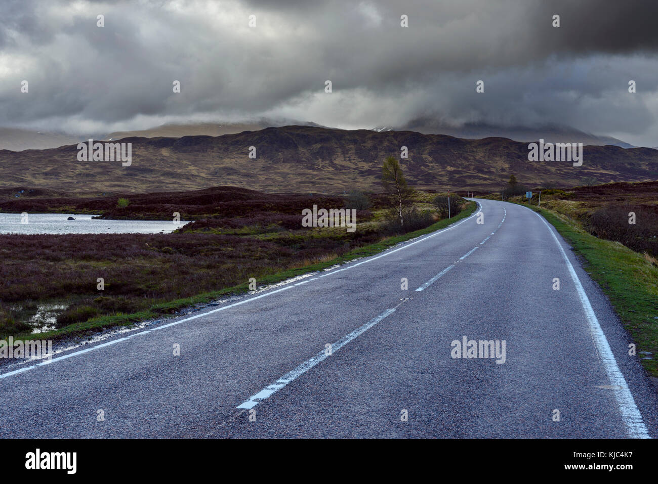 Country road through moor landscape with storm clouds at Rannoch Moor ...