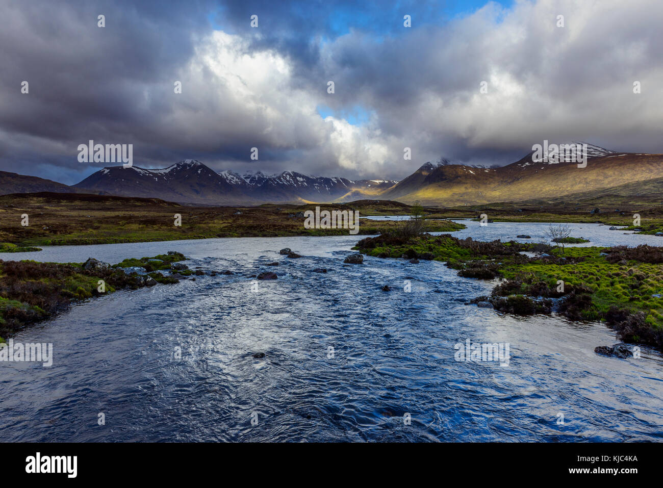 River in moor landscape with cloudy sky and mountains in the background ...