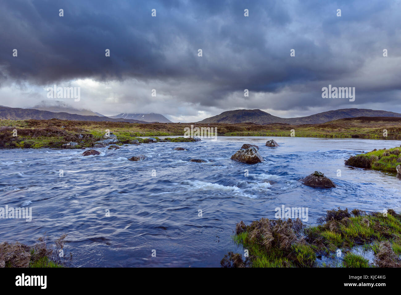 River in moor landscape with dark storm clouds with mountains in the ...