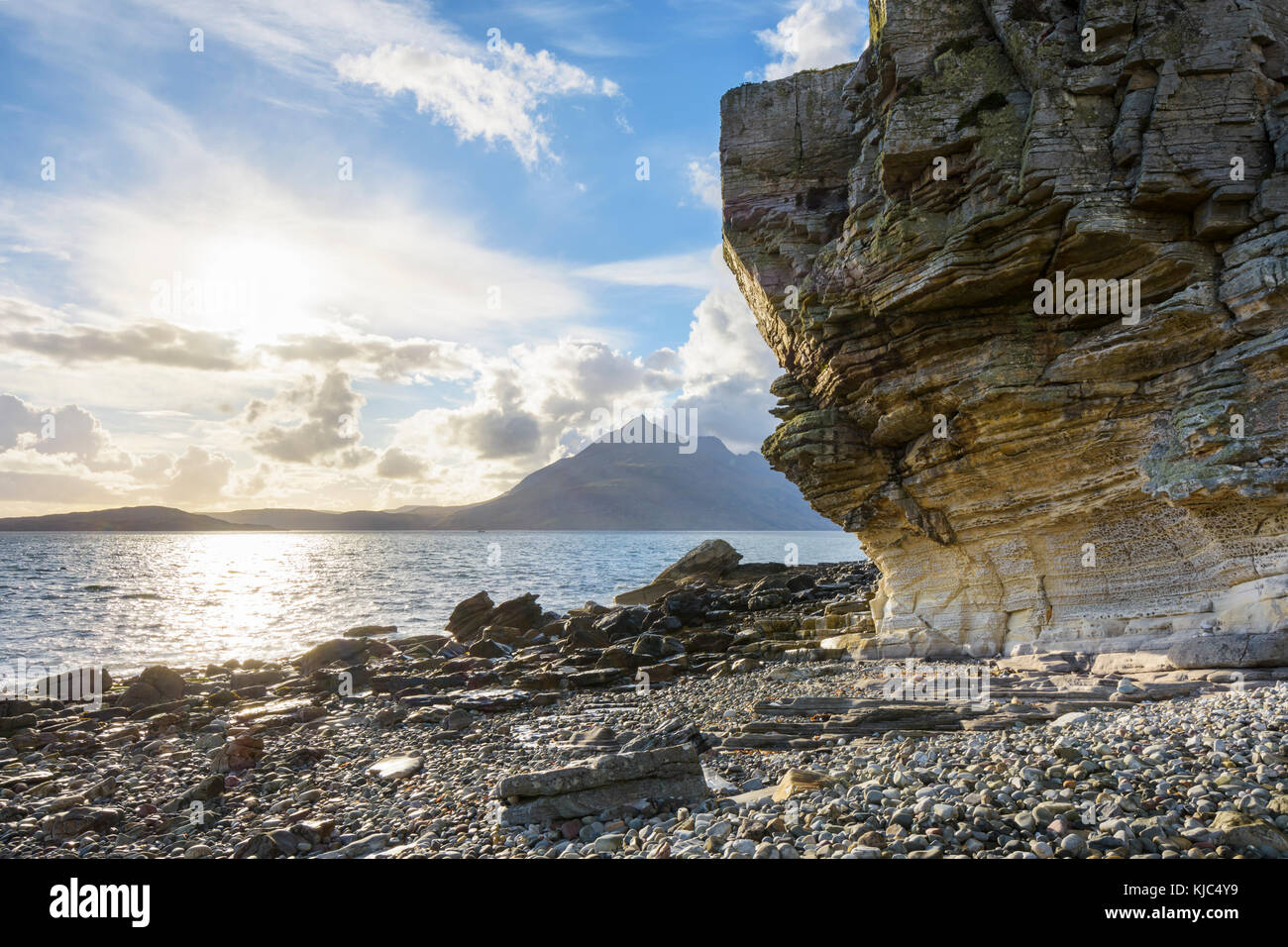 Rock face of sea cliff with honeycomb weathering and sun shining over ...