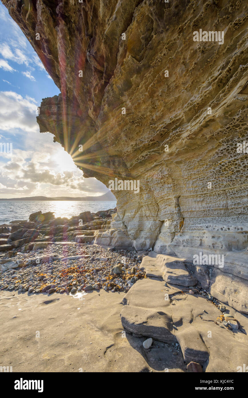 Close-up of rock face of sea cliff with honeycomb weathering and sun ...