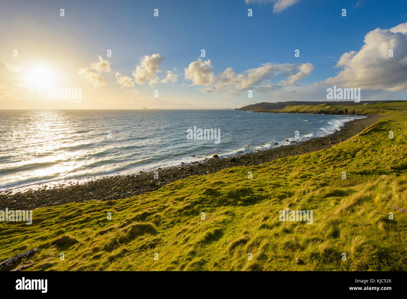 Rocky coastal beach with sun shining over the ocean on the Isle of Skye ...