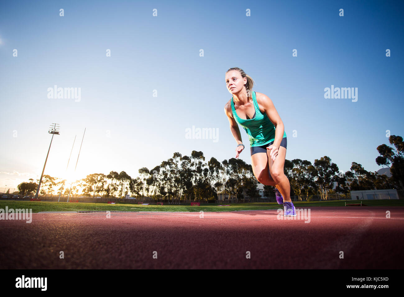 Close up wide angle view of a female sprinter athlete getting ready to ...
