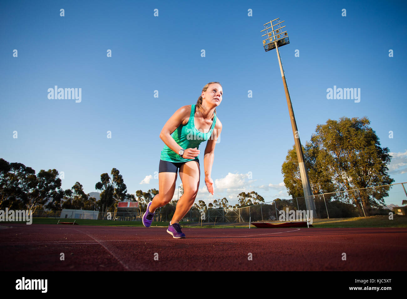 Close up wide angle view of a female sprinter athlete getting ready to ...