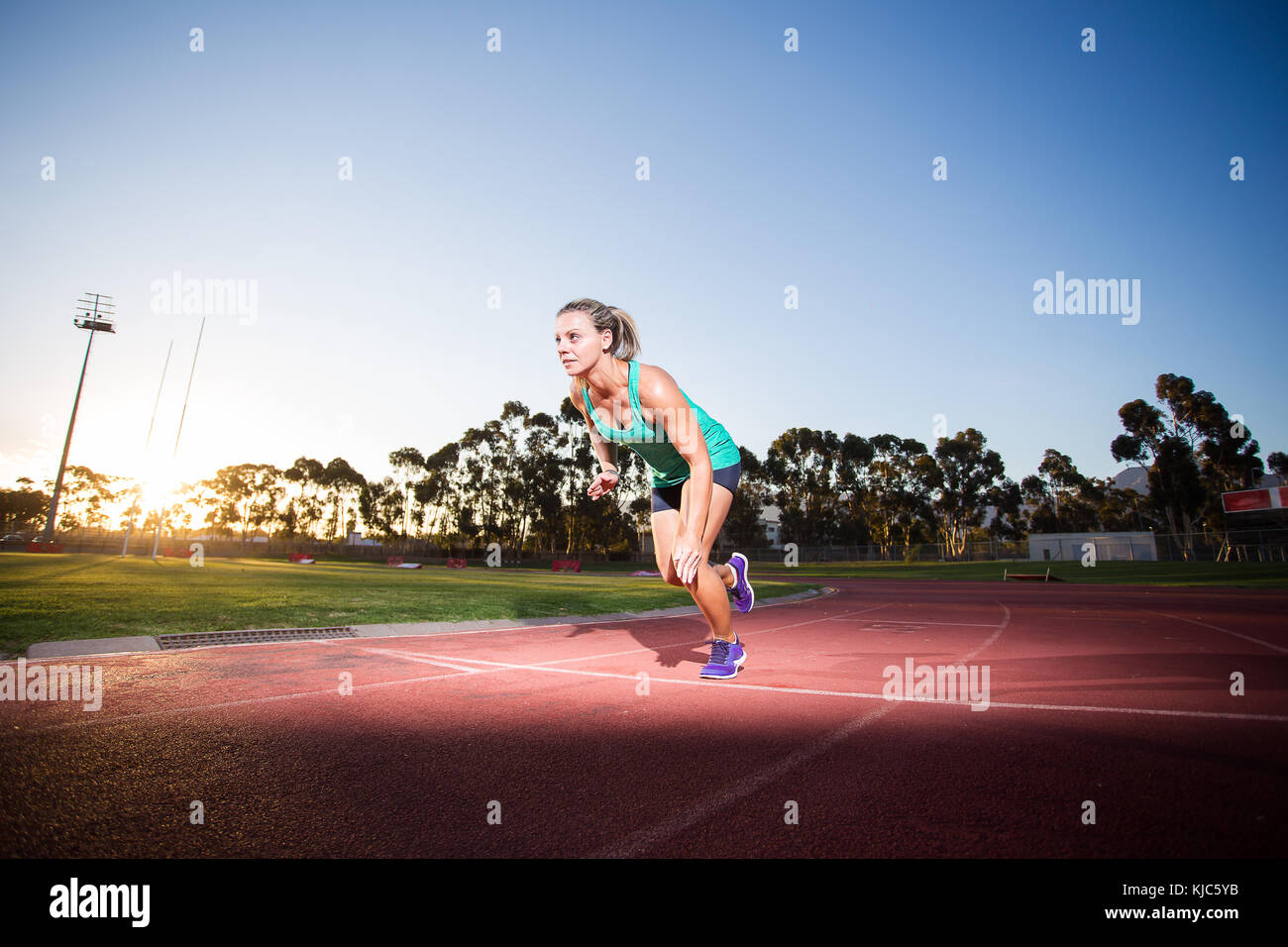 Close up wide angle view of a female sprinter athlete getting ready to ...
