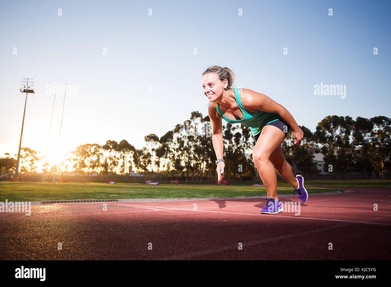 Close up wide angle view of a female sprinter athlete getting ready to ...