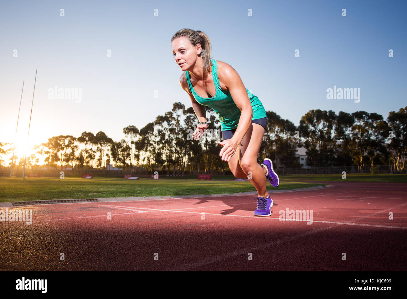 Close up wide angle view of a female sprinter athlete getting ready to ...