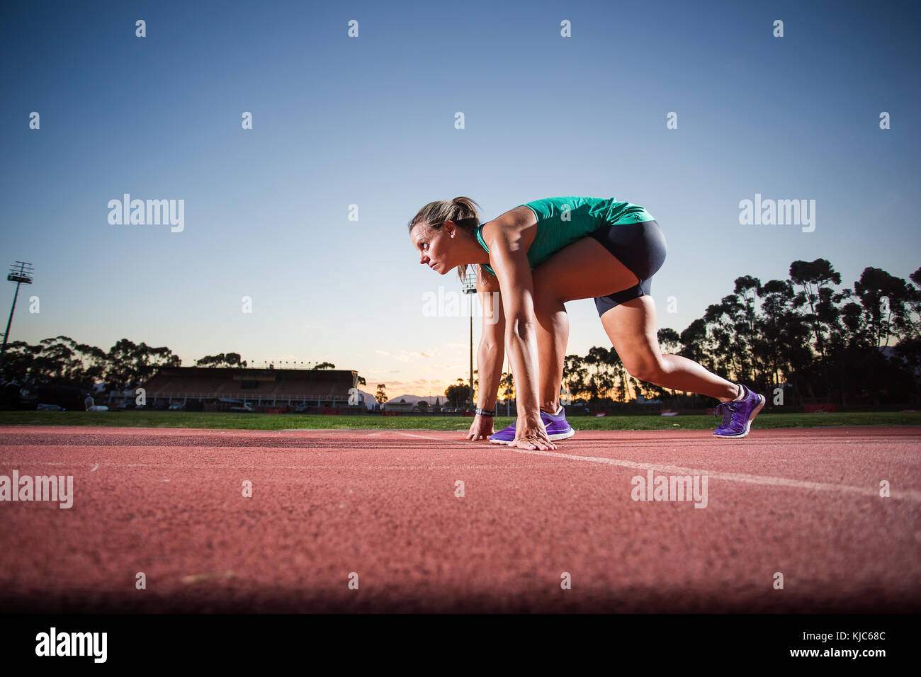 Close up wide angle view of a female sprinter athlete getting ready to ...