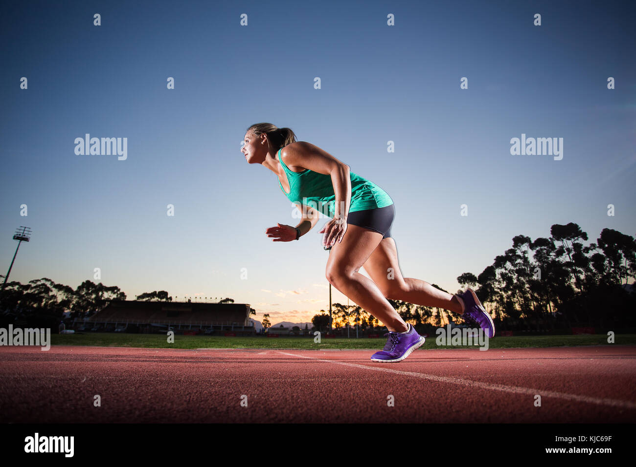 Close up wide angle view of a female sprinter athlete getting ready to ...