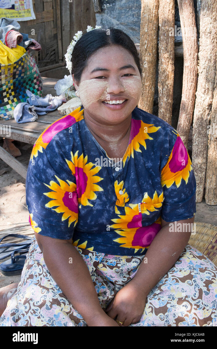 Young Burmese woman with tanakha paste on her face selling thanaka ...