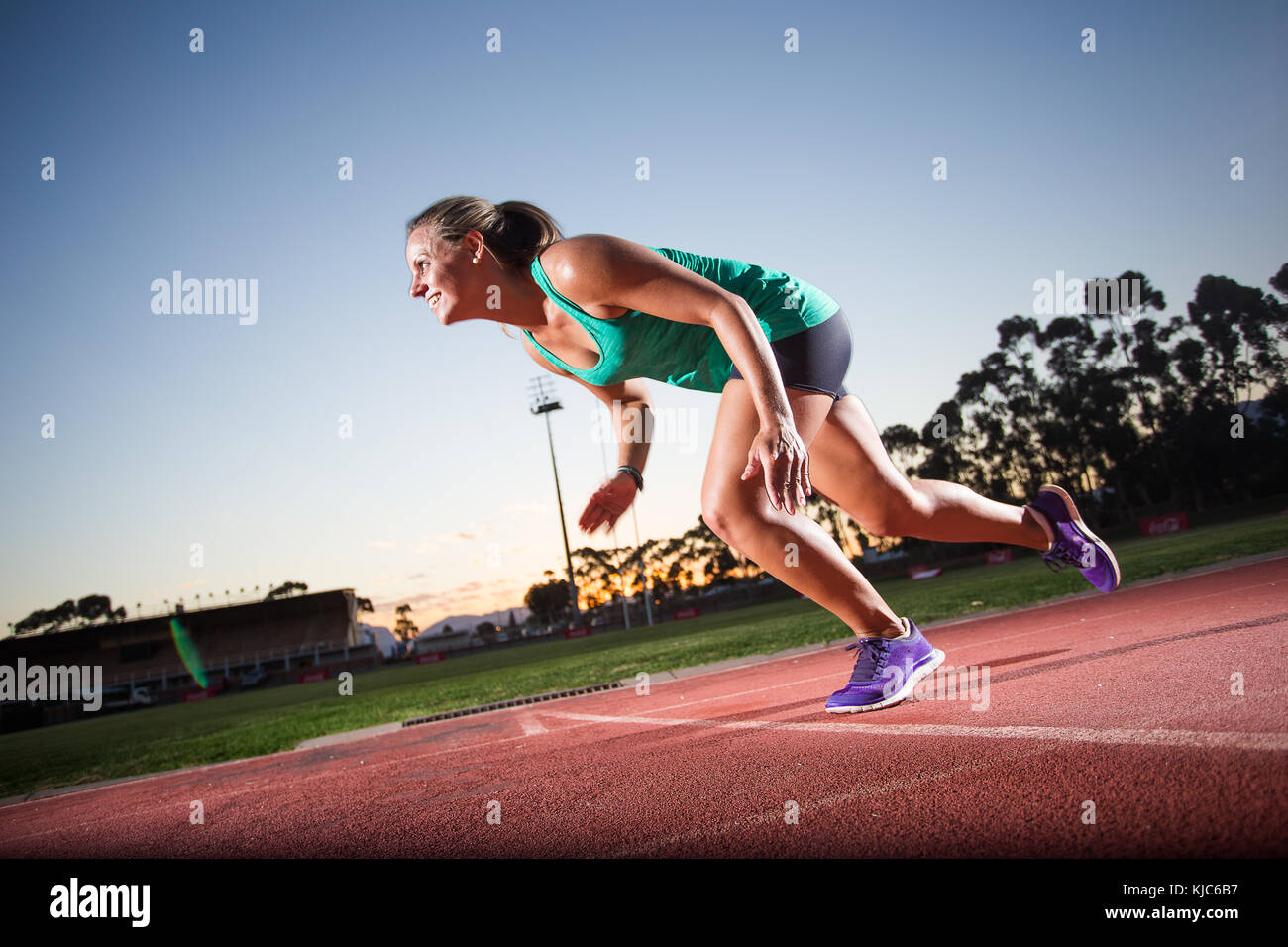 Close up wide angle view of a female sprinter athlete getting ready to ...