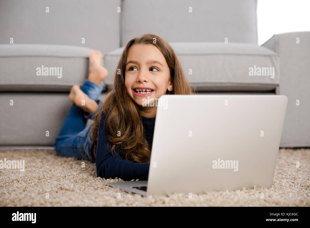 Happy little girl at home working with a laptop Stock Photo - Alamy