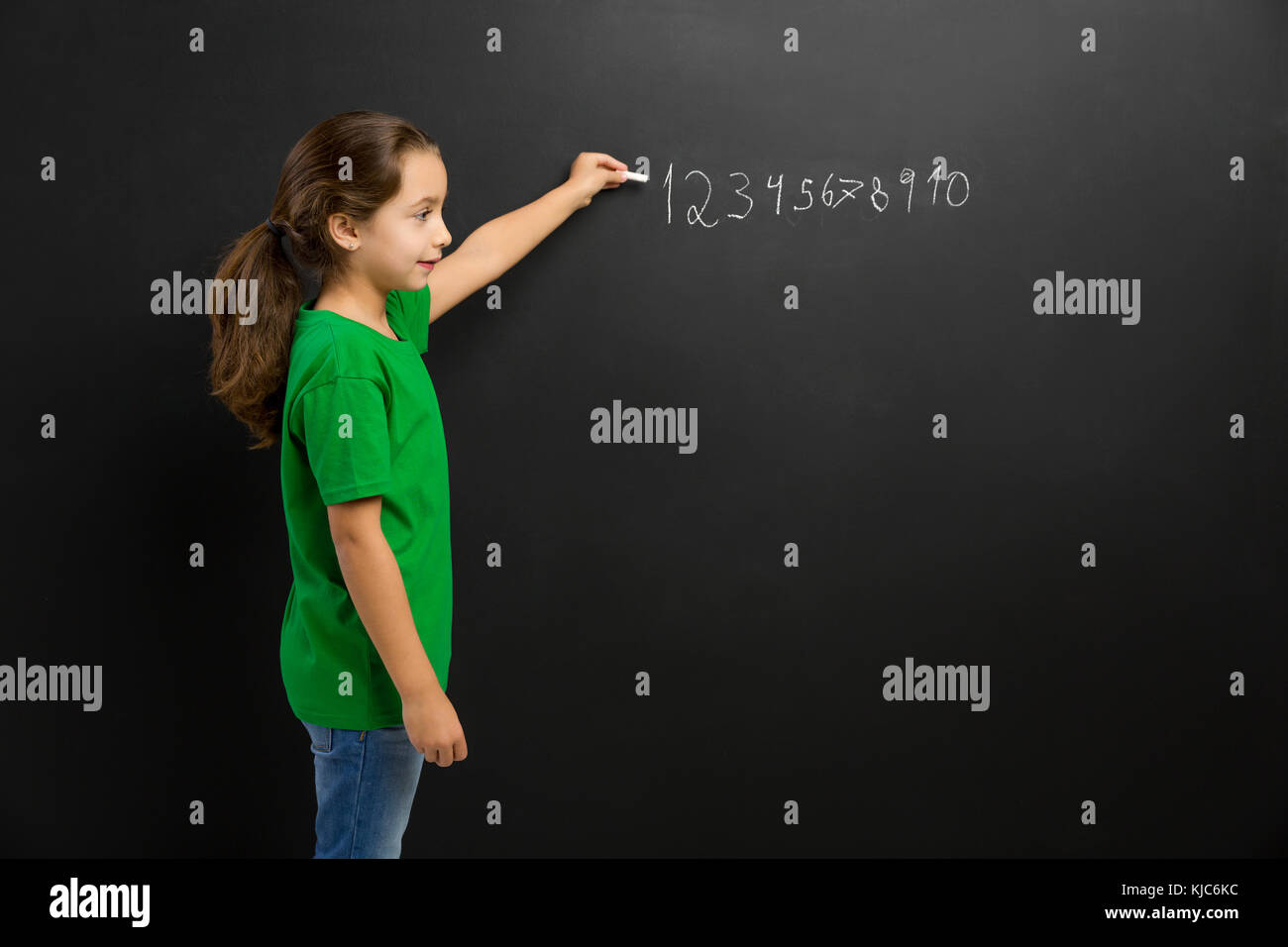 Smart little girl writing in a blackboard, with copy space Stock Photo ...