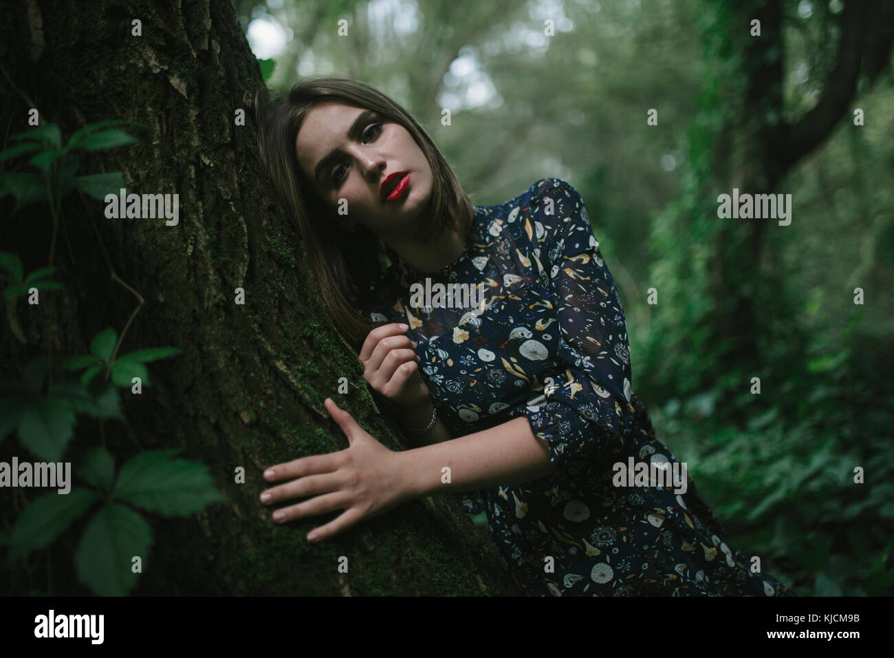 Caucasian woman leaning on tree trunk Stock Photo - Alamy
