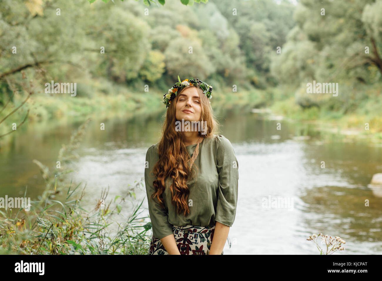 Middle Eastern woman wearing flower crown near river Stock Photo - Alamy