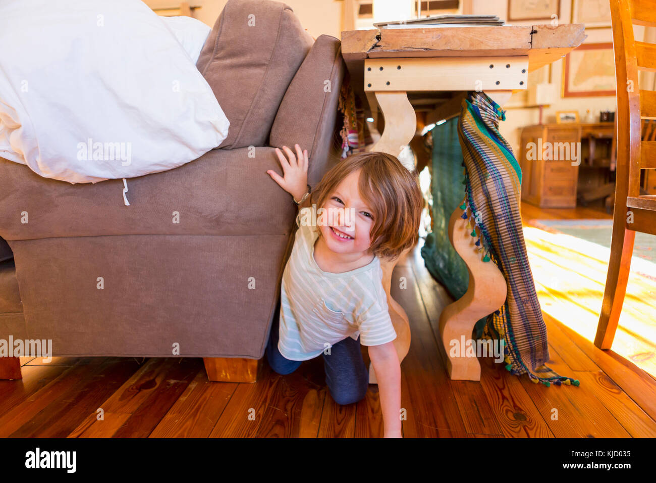 Caucasian boy crawling on floor between table and sofa Stock Photo - Alamy