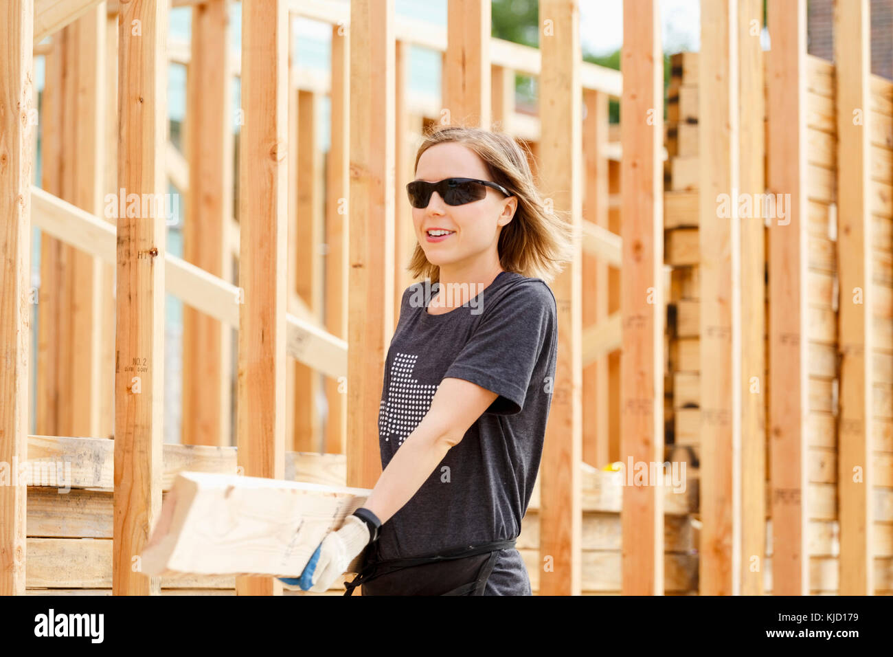 Caucasian woman carrying lumber at construction site Stock Photo - Alamy