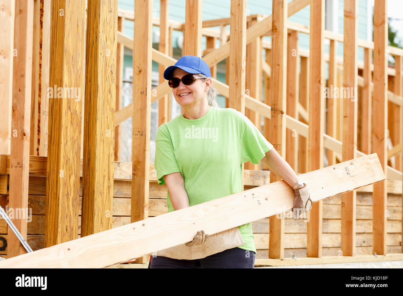 Caucasian woman carrying lumber at construction site Stock Photo - Alamy