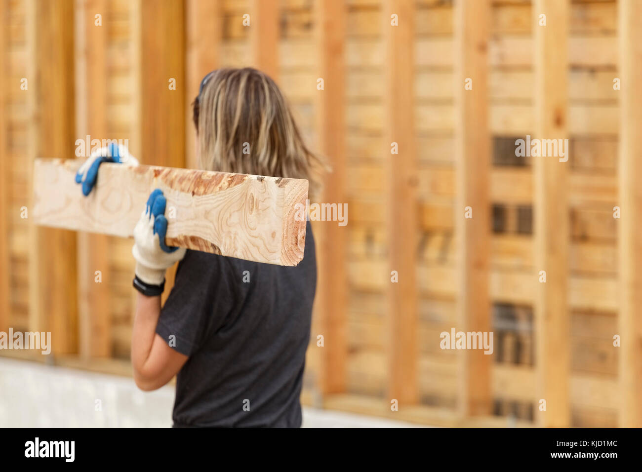 Caucasian woman carrying lumber at construction site Stock Photo - Alamy