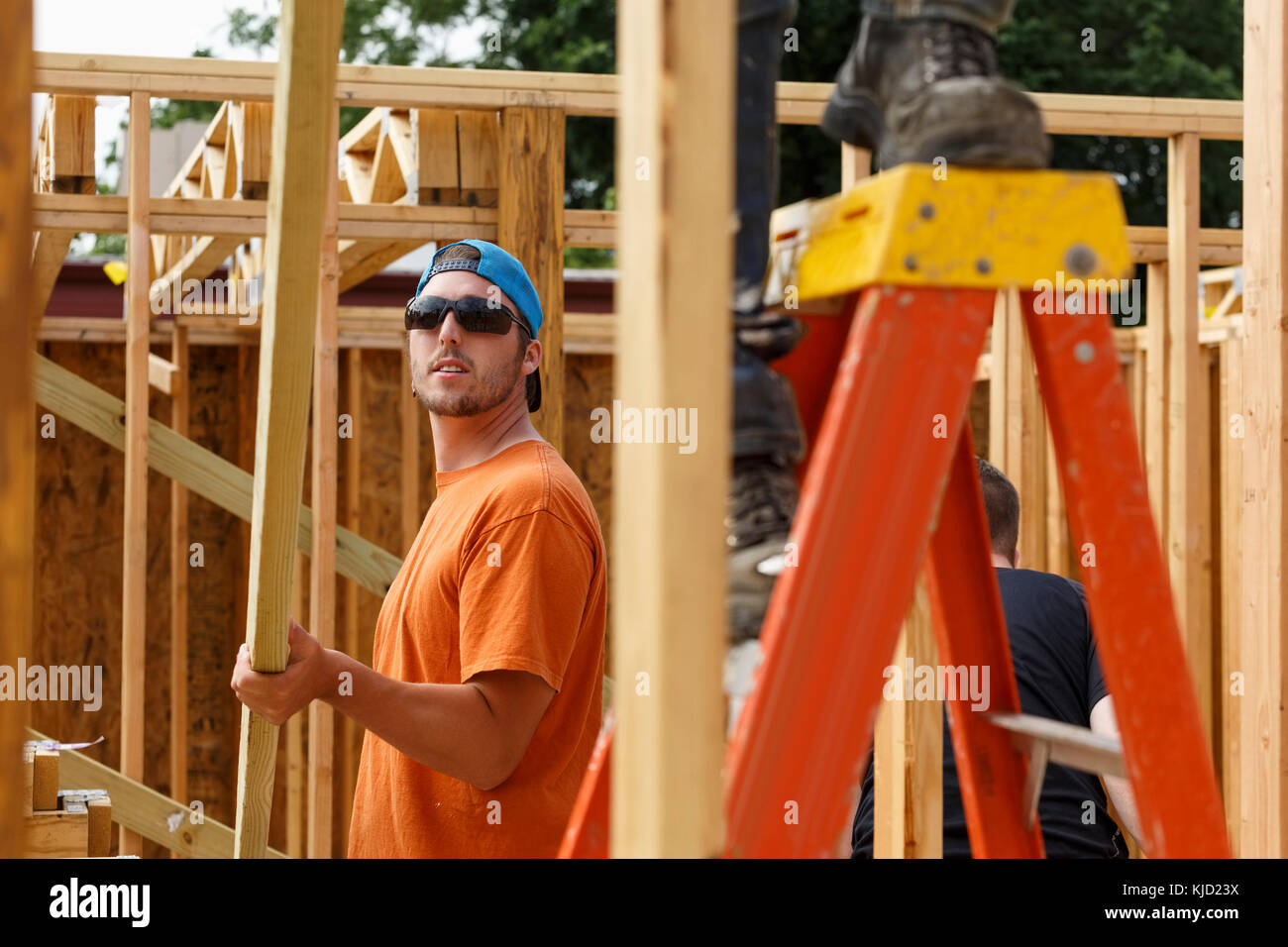 Caucasian man lifting lumber at construction site Stock Photo - Alamy