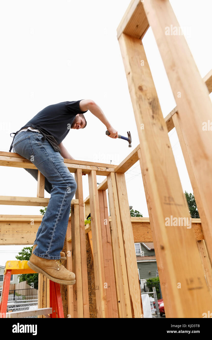 Caucasian man hammering nail at construction site Stock Photo - Alamy