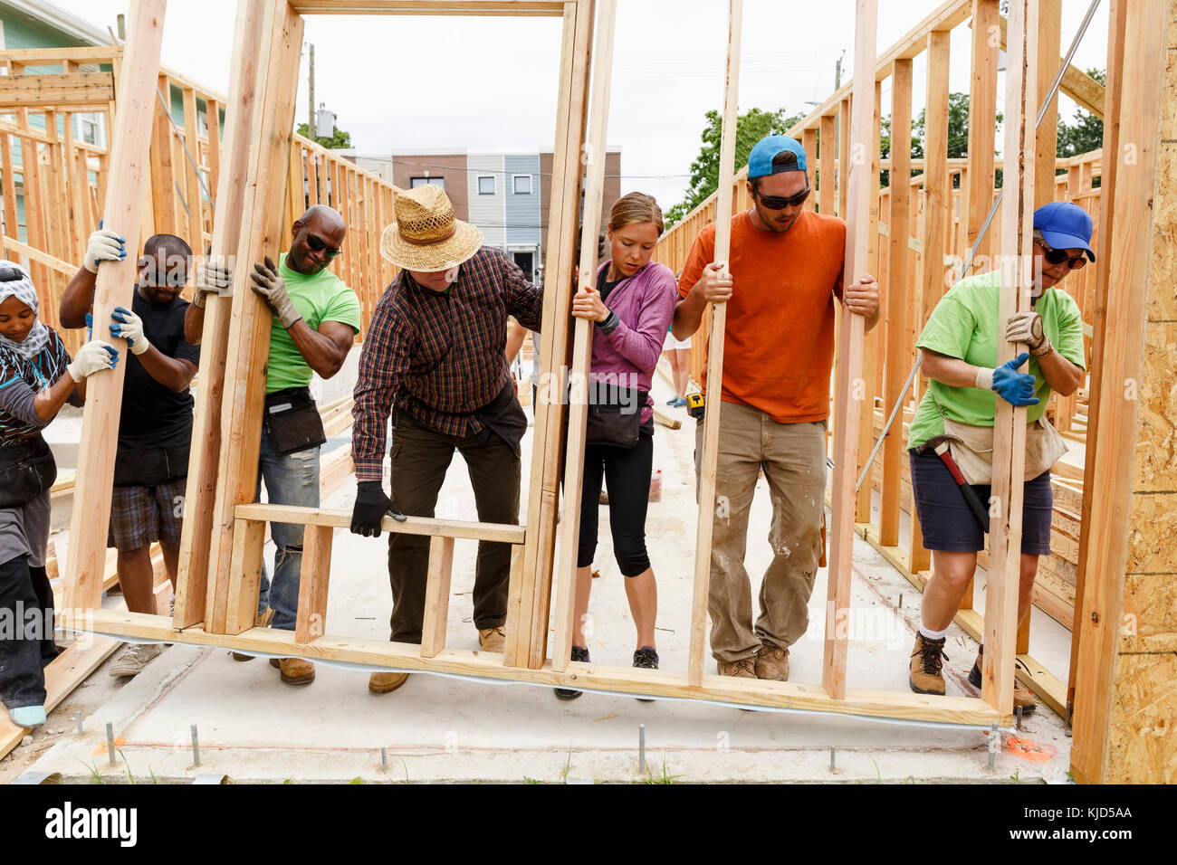 Volunteers lifting wall at construction site Stock Photo - Alamy