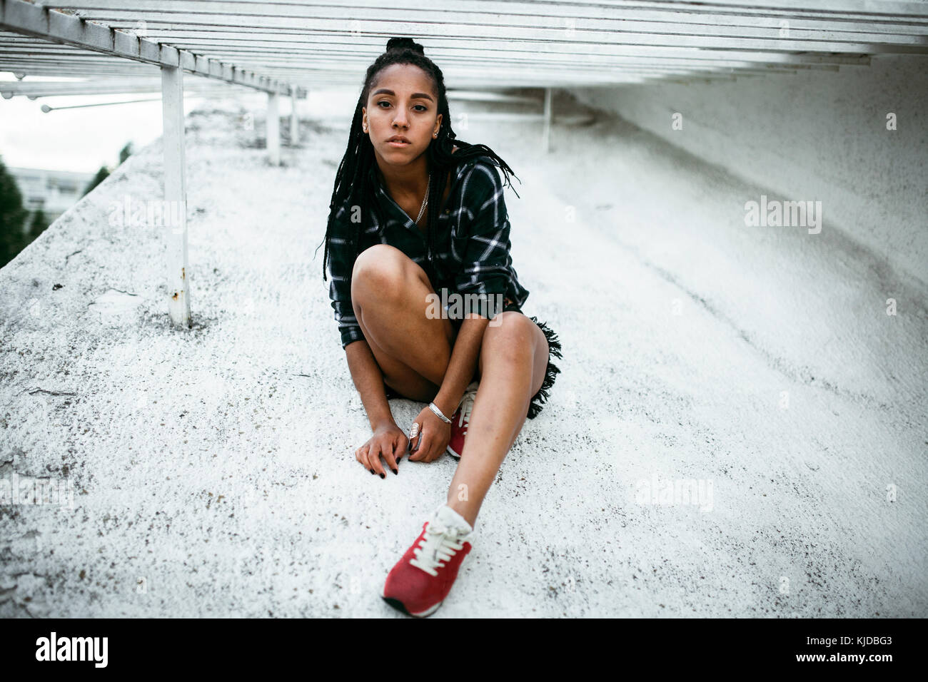 Portrait of serious African American woman sitting on concrete Stock ...