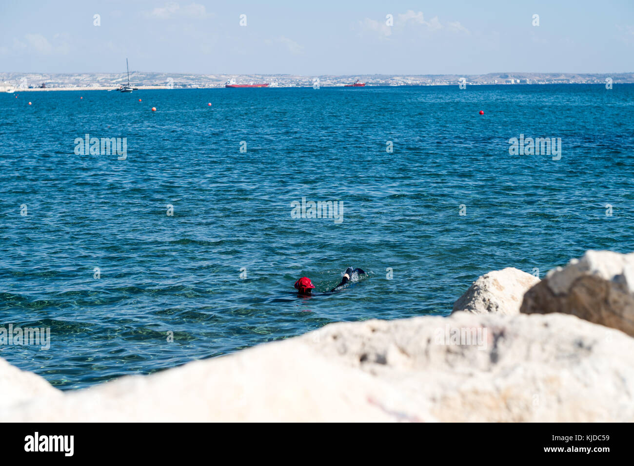 Tourist swimming in the sea and view of Larnaca bay from fishing pier ...