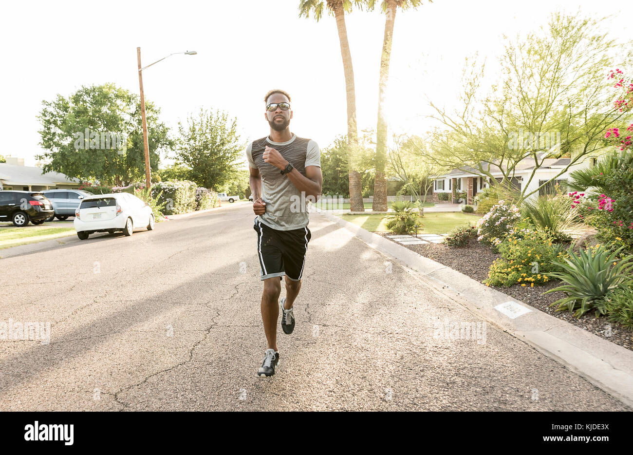 Black man running on street in neighborhood Stock Photo - Alamy