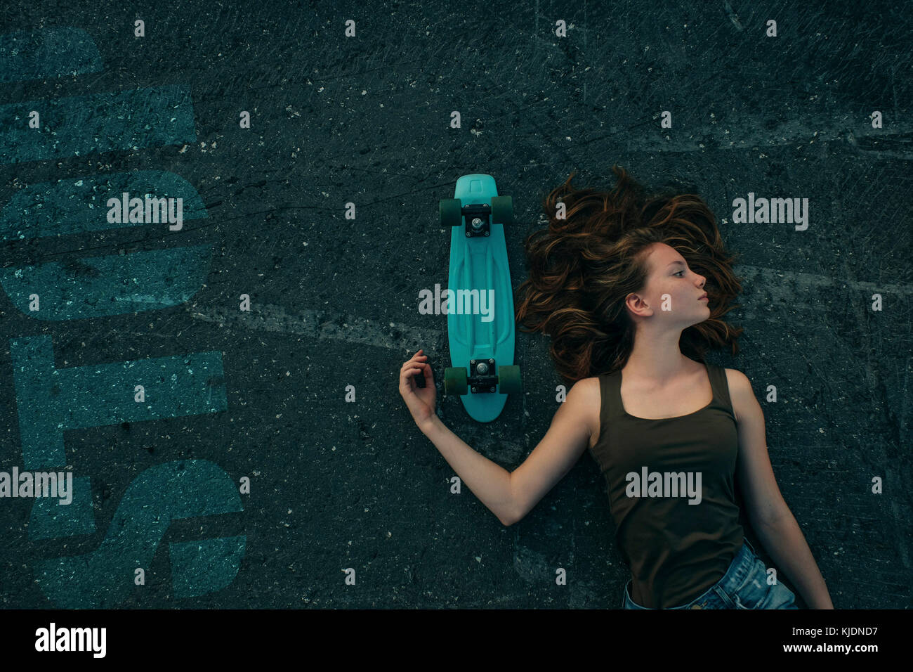 Caucasian teenage girl laying on pavement with skateboard Stock Photo ...