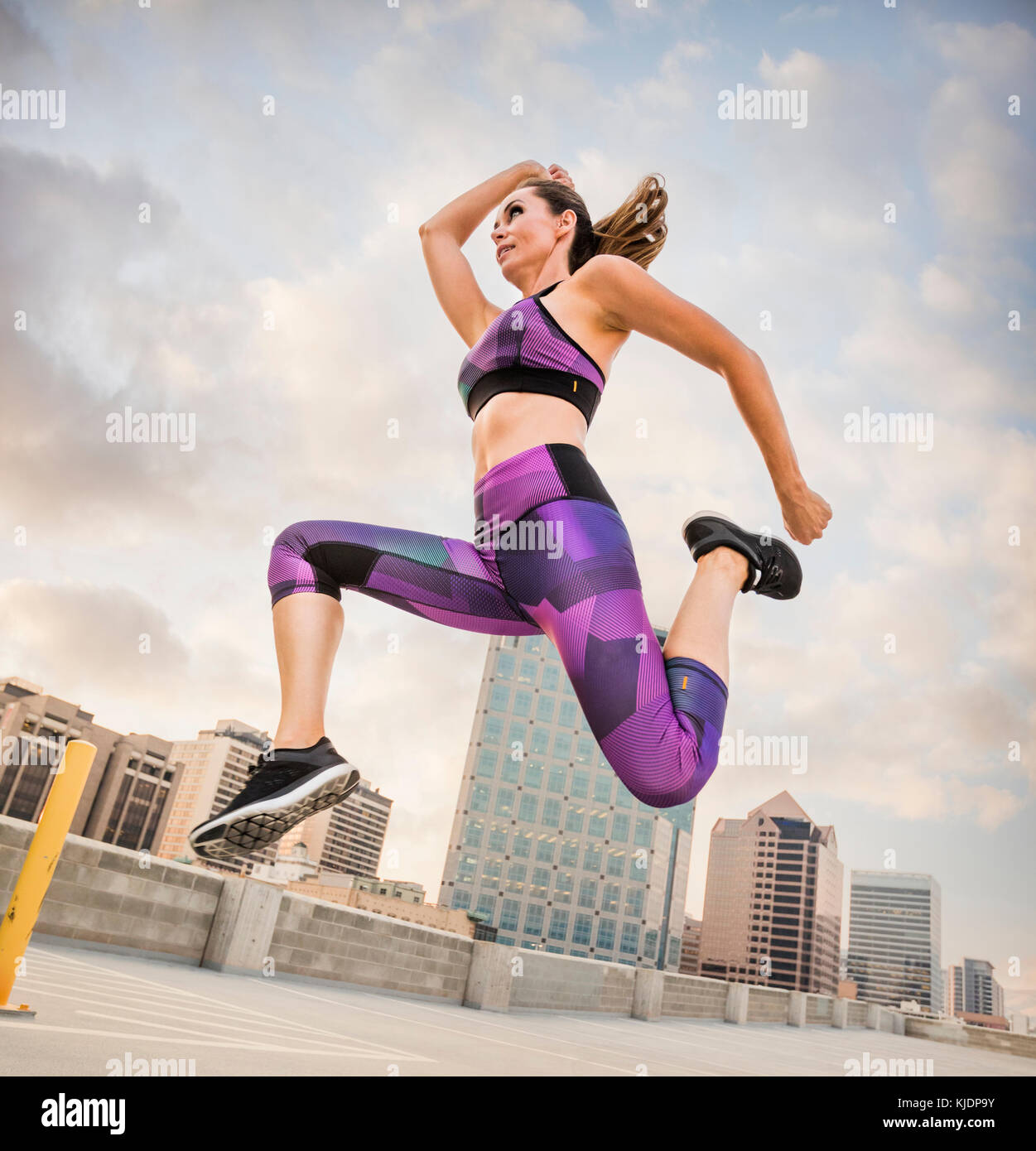 Caucasian woman running and jumping on urban rooftop Stock Photo - Alamy