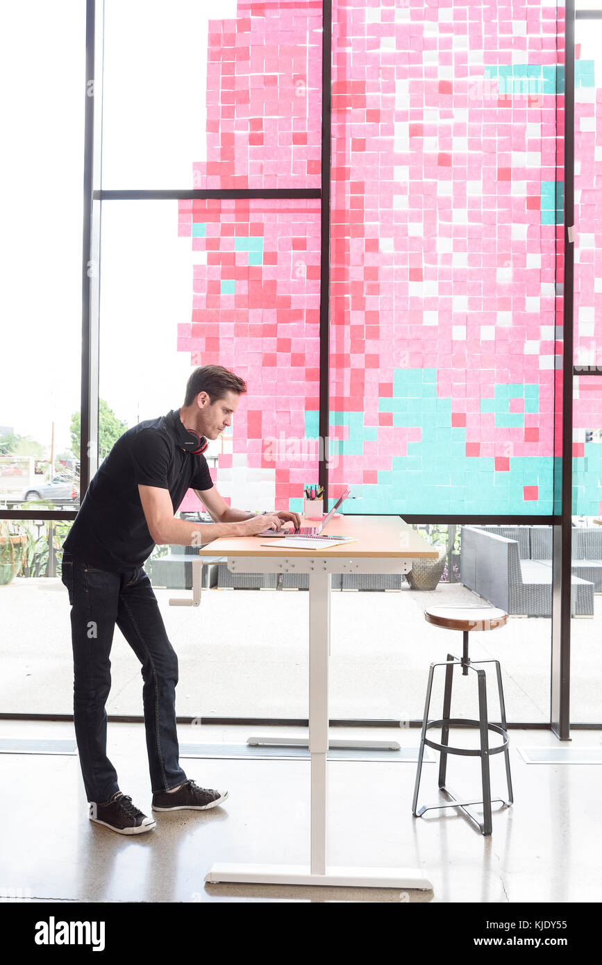 Caucasian man using a laptop at standing workstation Stock Photo - Alamy