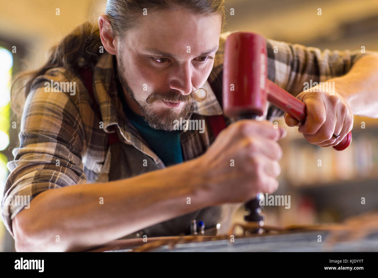 Caucasian man hammering leather Stock Photo - Alamy