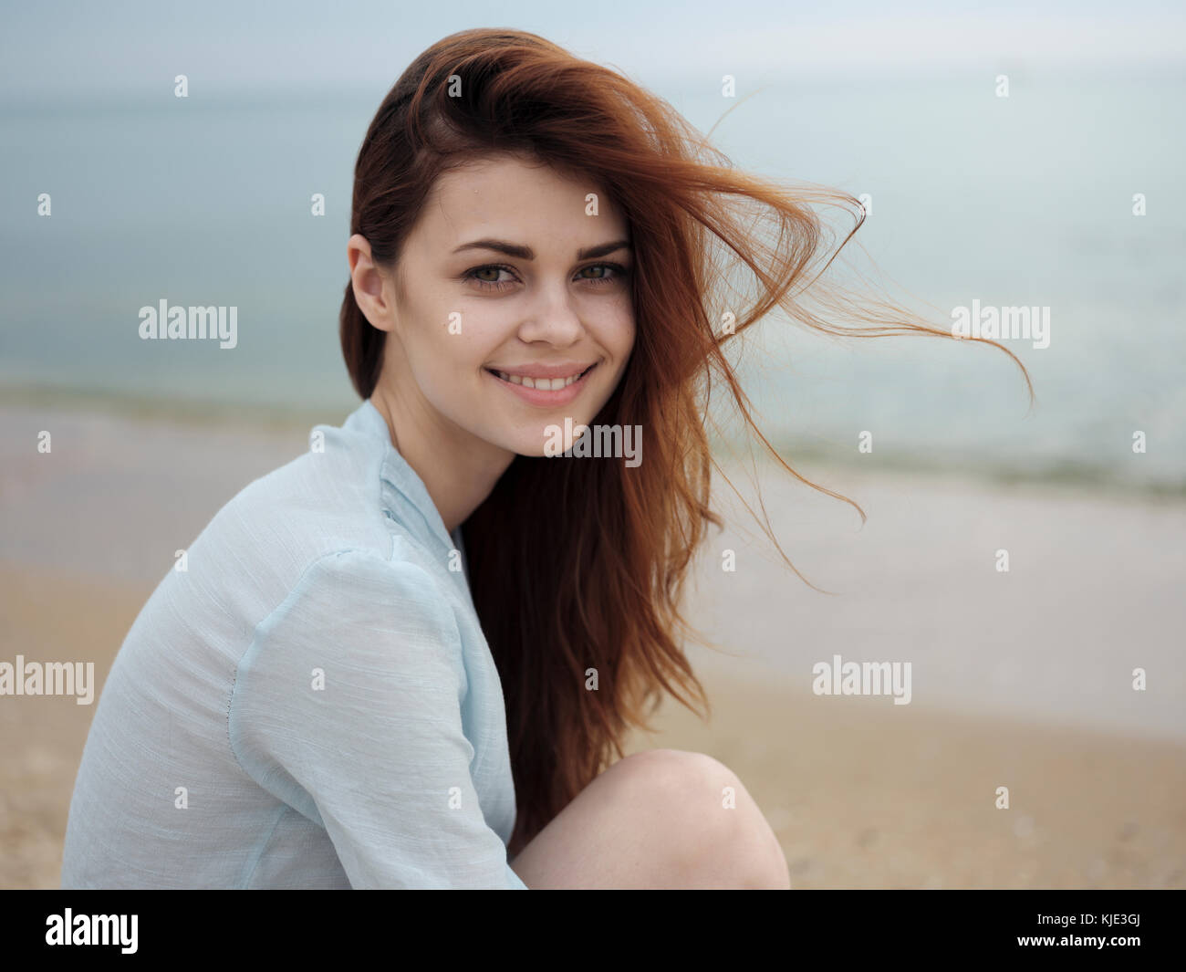 Wind blowing hair of Caucasian woman sitting on the beach Stock Photo ...