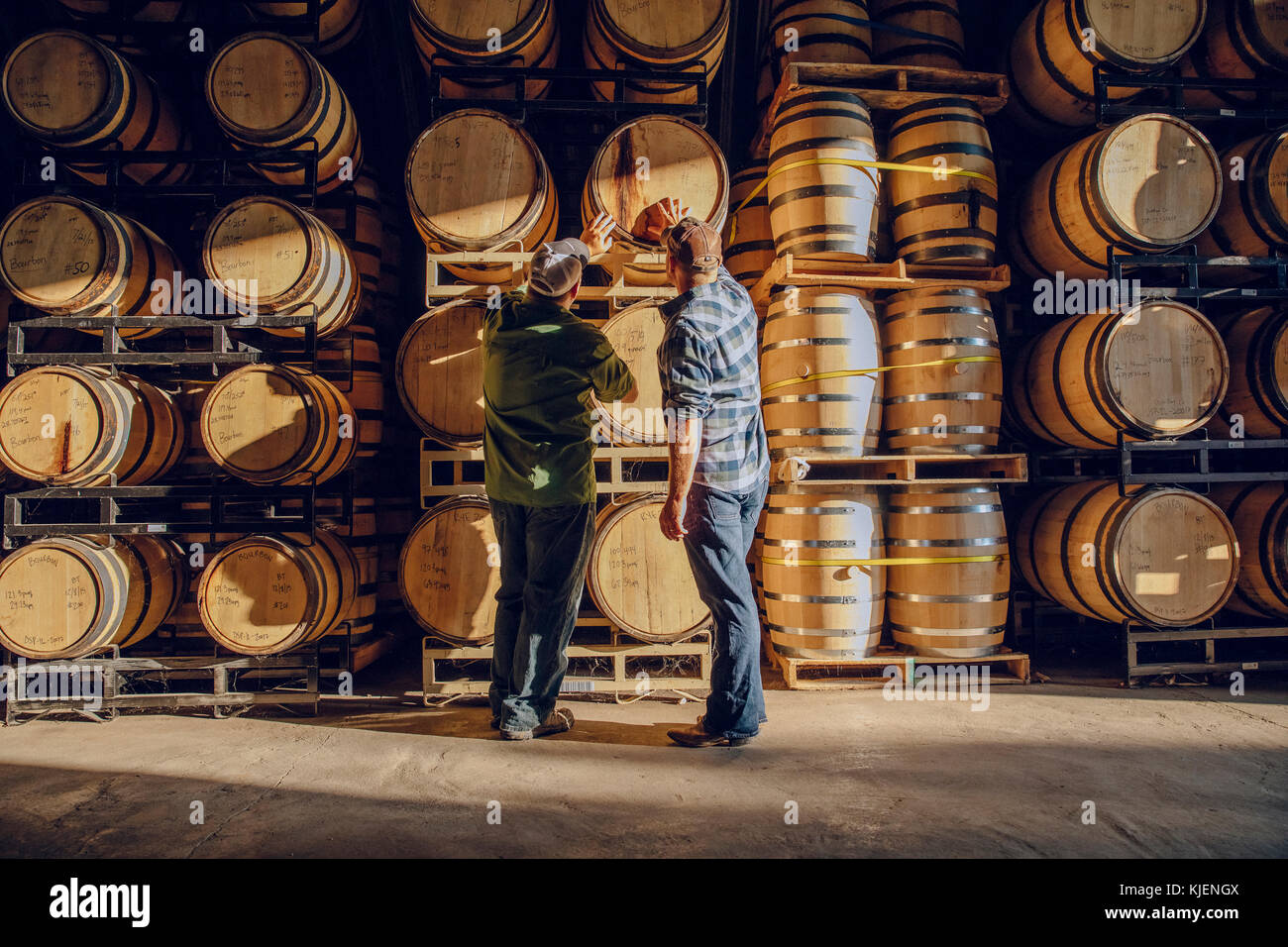 Caucasian men examining barrel in distillery Stock Photo - Alamy