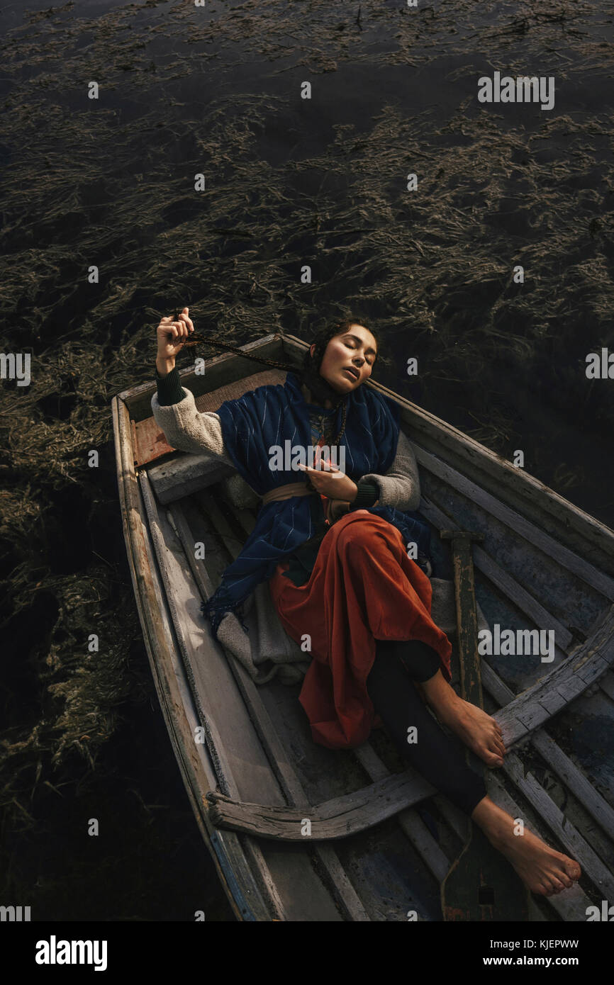 Location woman wearing traditional clothing laying in rowboat Stock ...