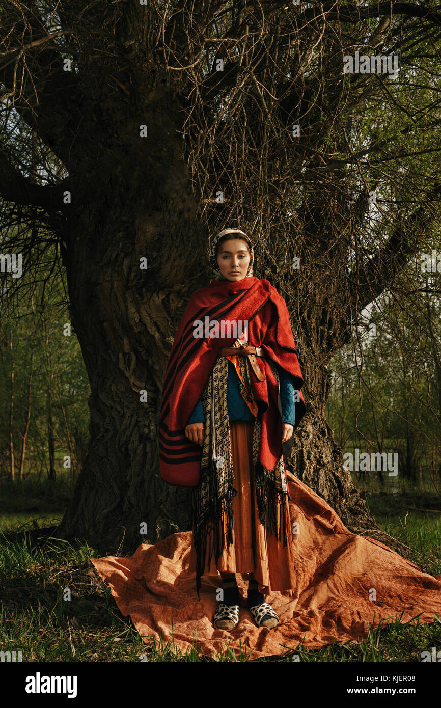 Caucasian woman wearing traditional clothing standing near tree Stock ...