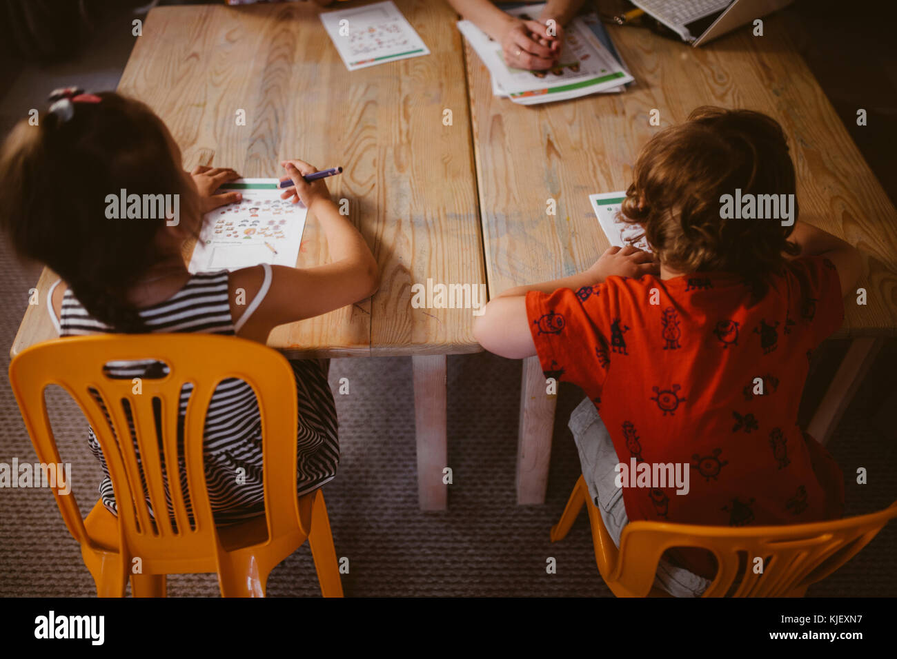 Caucasian boy and girl sitting at table coloring Stock Photo - Alamy