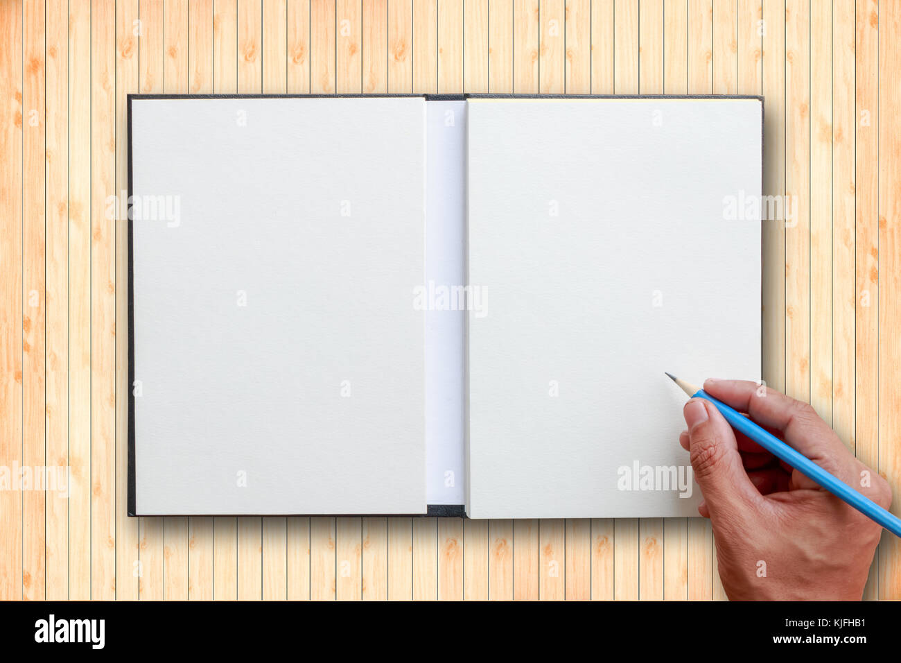 Human hand use blue pencil to write open notebook put on brown wooden ...