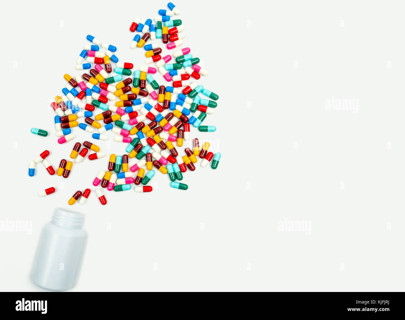 Pouring antibiotics capsule pills into plastic bottle on white ...