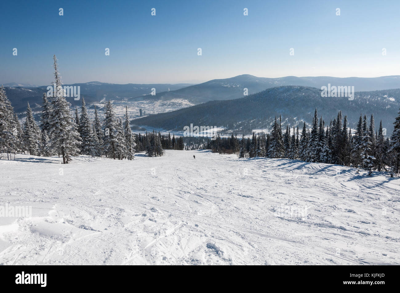Top view of the mountain snow slope, ski tracks, forest and the village ...