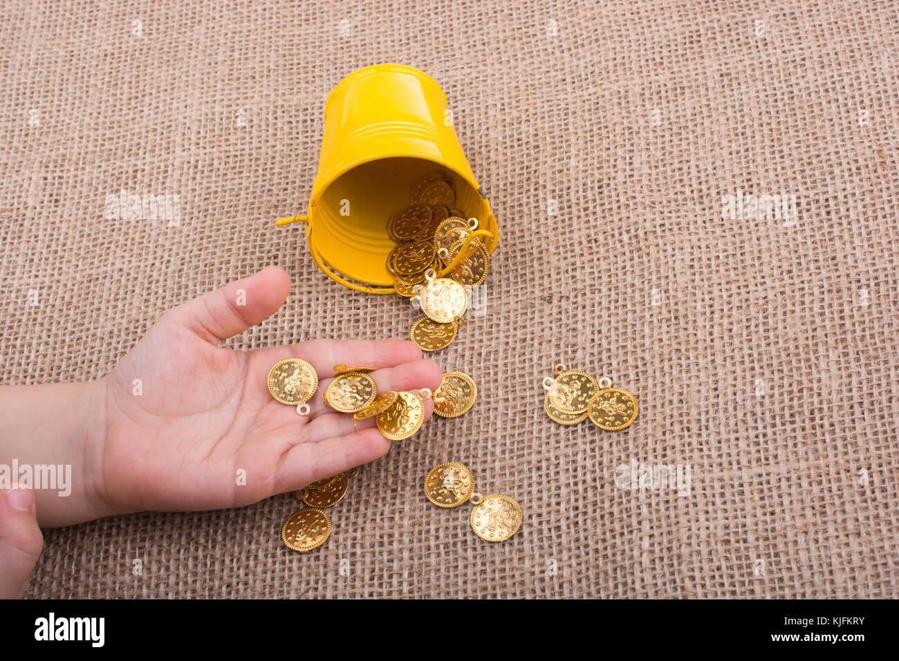 Bucket and fake gold coins in hand on canvas background Stock Photo - Alamy