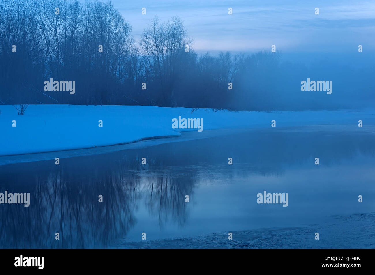 Night landscape with the river, partially covered with ice, snow on the ...