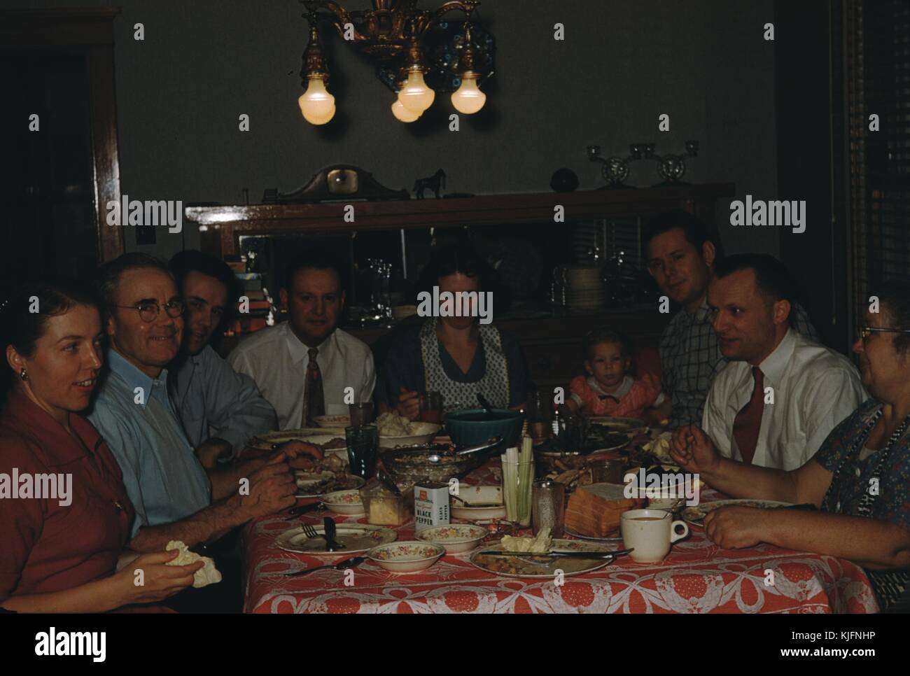 A photograph of a family sitting for dinner together at a table, three ...