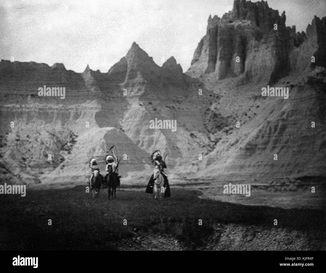 Photograph of three Native American men, on horseback, wearing large ...