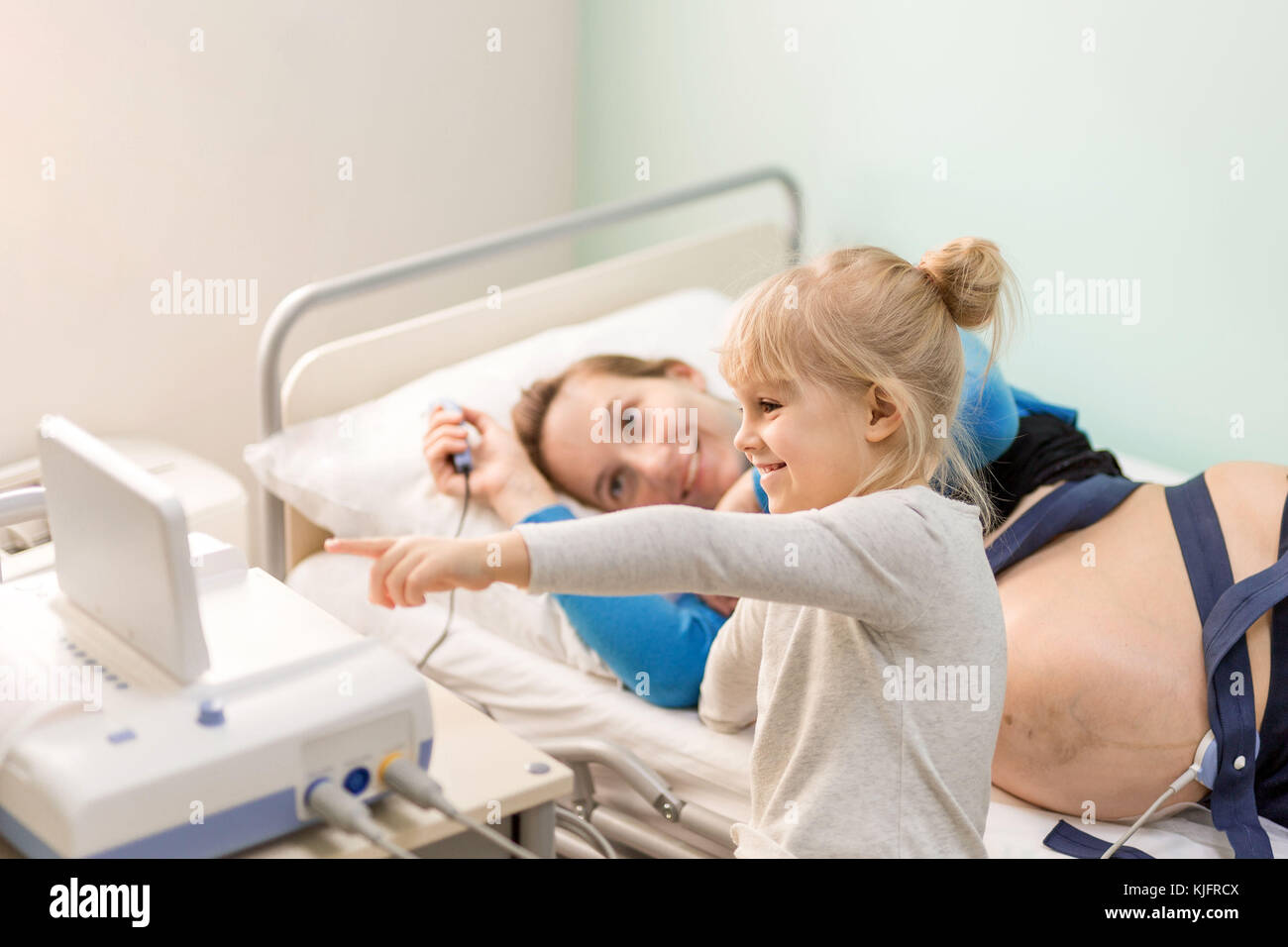 Pregnant woman with daughter smiling and looking to the display during ...
