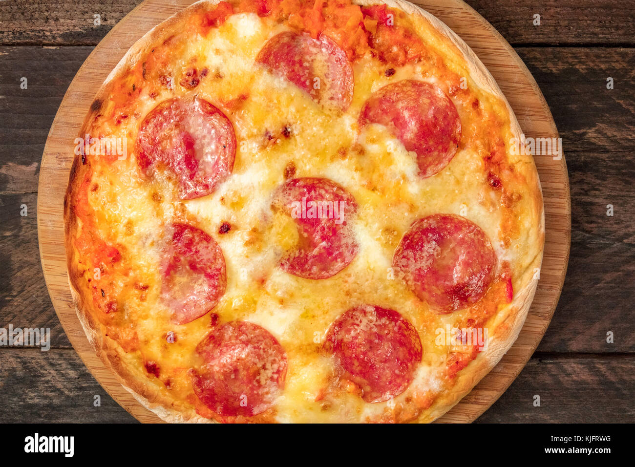 Cut pepperoni pizza on rustic texture, overhead closeup Stock Photo - Alamy
