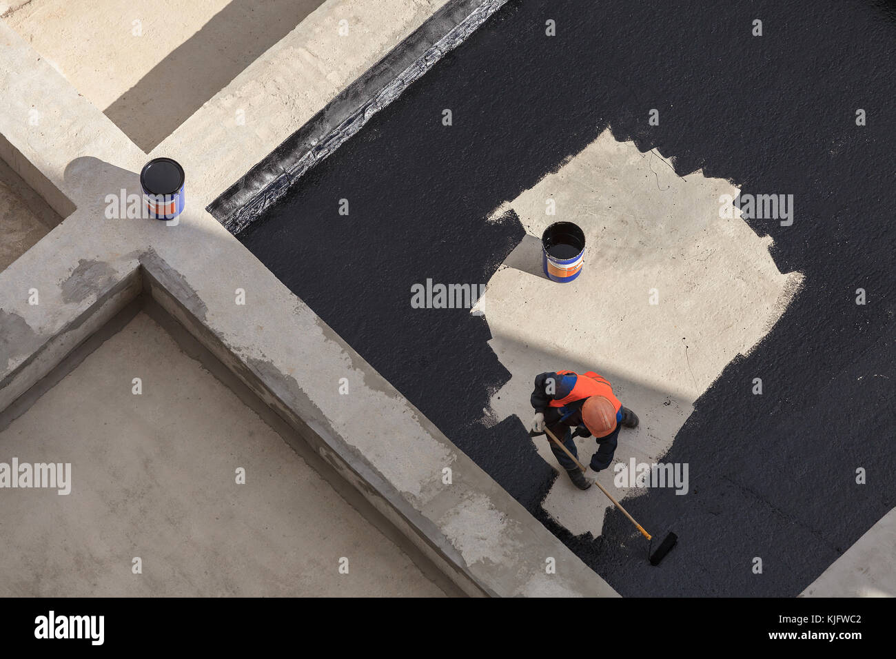 The worker in overalls applies an insulation coating on the concrete ...